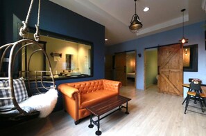 Quarto com poltrona suspensa, sofá, mesa de jantar com cadeiras e porta de madeira.
