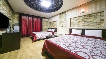 Quarto de hotel com duas camas, um espelho grande, uma televisão e uma parede de pedra.
