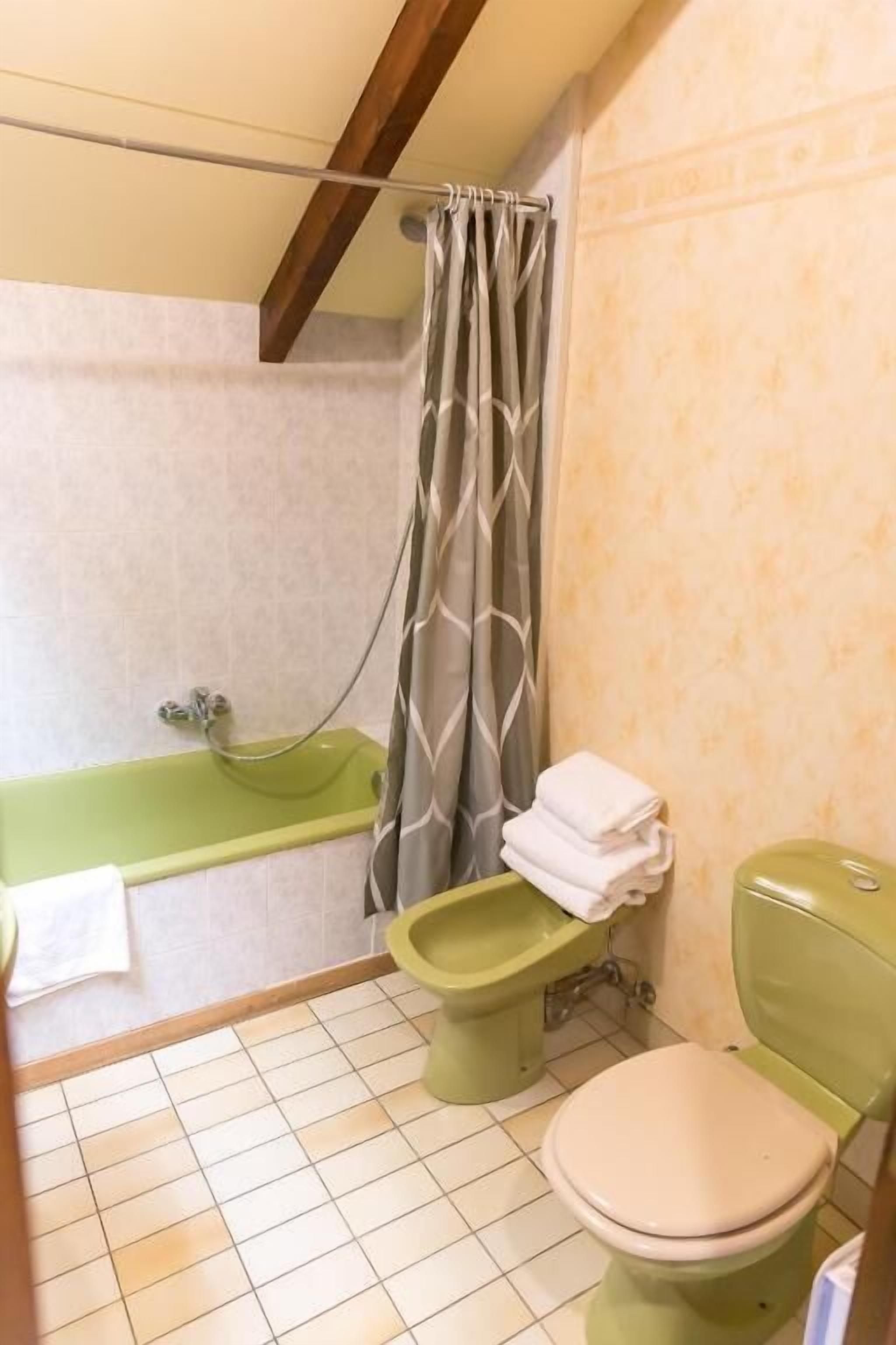 Casa de banho com banheira verde, bidé e sanita.