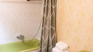 Casa de banho com banheira verde, bidé e sanita.