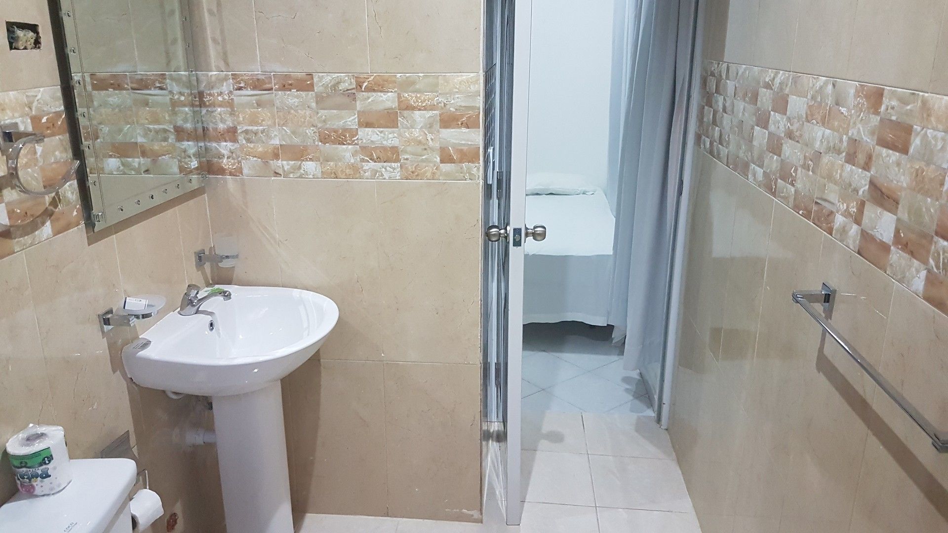 Casa de banho com lavatório branco, sanita e zona de duche.