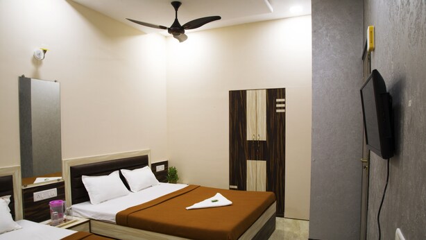 Quarto de hotel com duas camas, ventoinha no teto, televisão e minibar.