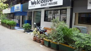 Uma casa de hóspedes com placa, aparelhos de ar condicionado e plantas em vasos na frente.