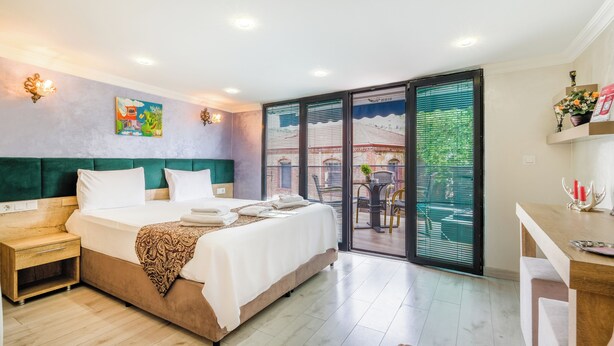 Quarto de hotel moderno com uma cama grande, uma escrivaninha e uma varanda com vista para a cidade.