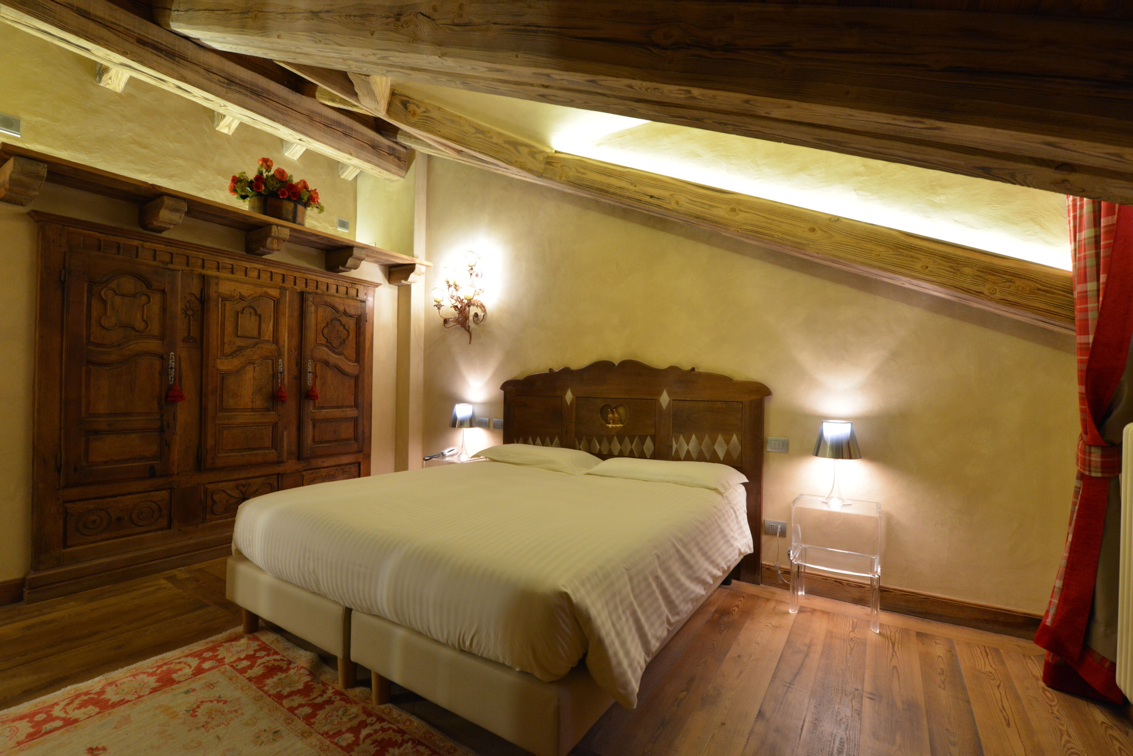 Quarto com cama de madeira, mesa de cabeceira, cômoda e mesa auxiliar.
