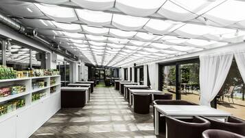 Um espaço interior moderno com teto estampado, mesas, cadeiras e vista para o exterior.