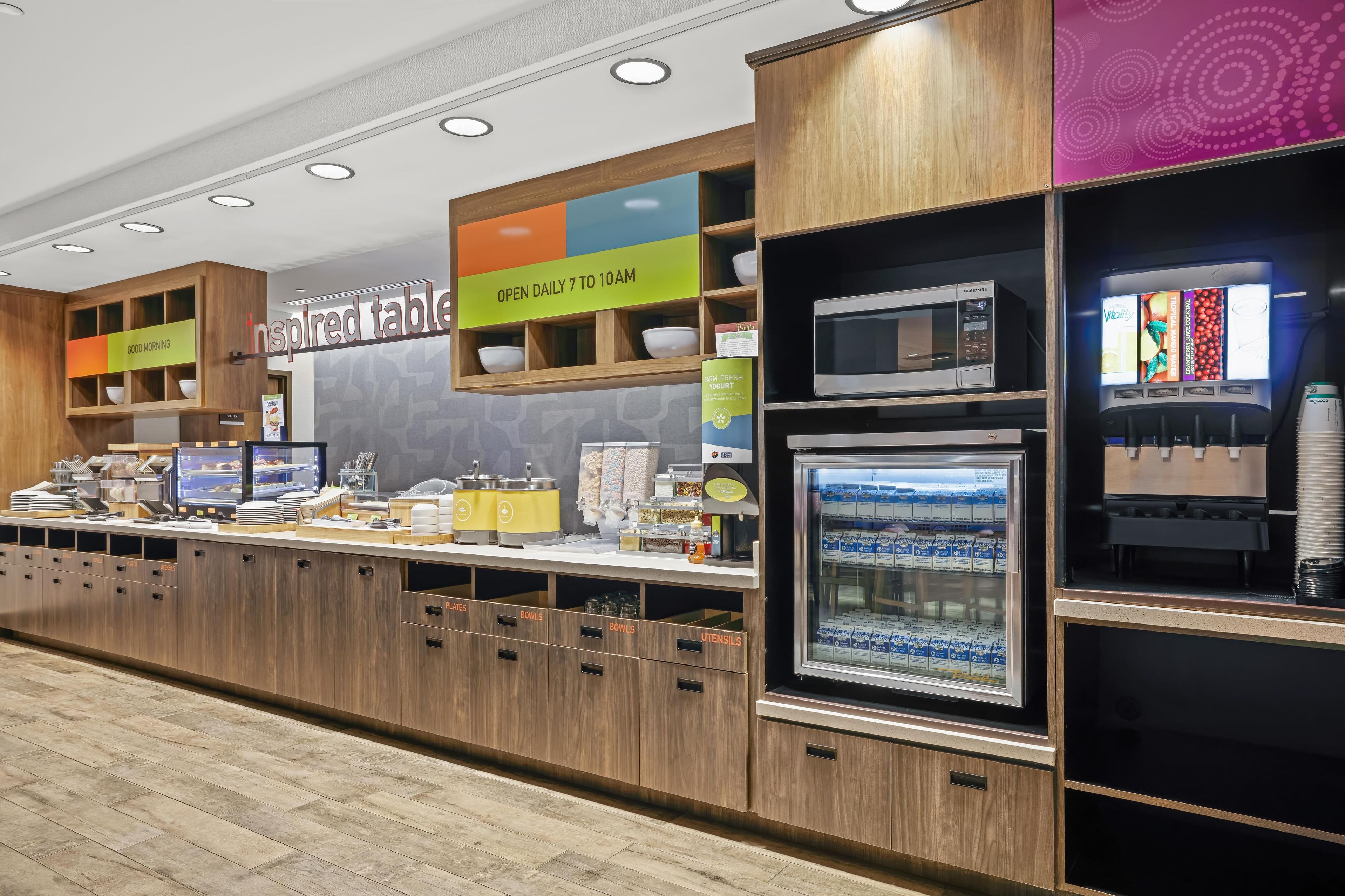 Espaço de café da manhã com serviço de autoatendimento, incluindo micro-ondas, geladeira e dispensador de bebidas.