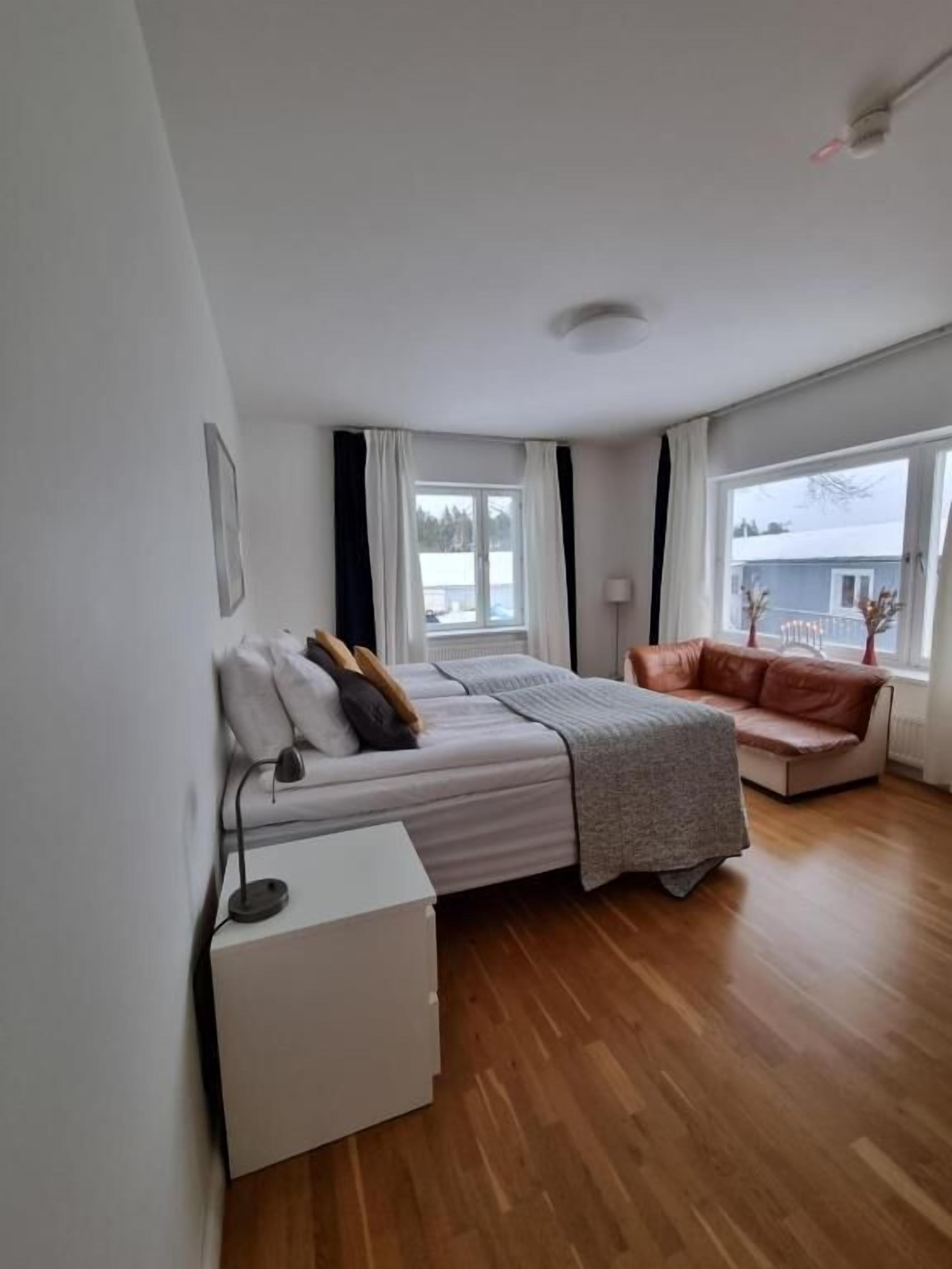 Quarto com cama, mesa de cabeceira, janela e vista para o exterior.
