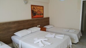 Quarto de hotel com duas camas de solteiro, cabeceira de madeira, pintura de folhas de outono e um pequeno baú de madeira.