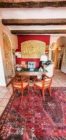 Uma área de refeições com uma mesa, cadeiras, uma parede vermelha e um tapete estampado.