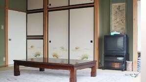 Um quarto japonês tradicional com tatames, uma mesa de madeira baixa e um painel deslizante shoji com motivos florais.