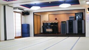 Quarto com esteiras de tatame, um tradicional divisório de ambiente japonês e uma televisão.