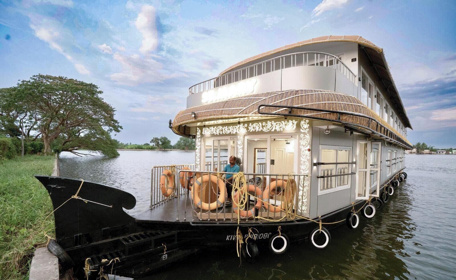 Uma casa flutuante com telhado curvo, vários decks e boias salva-vidas.