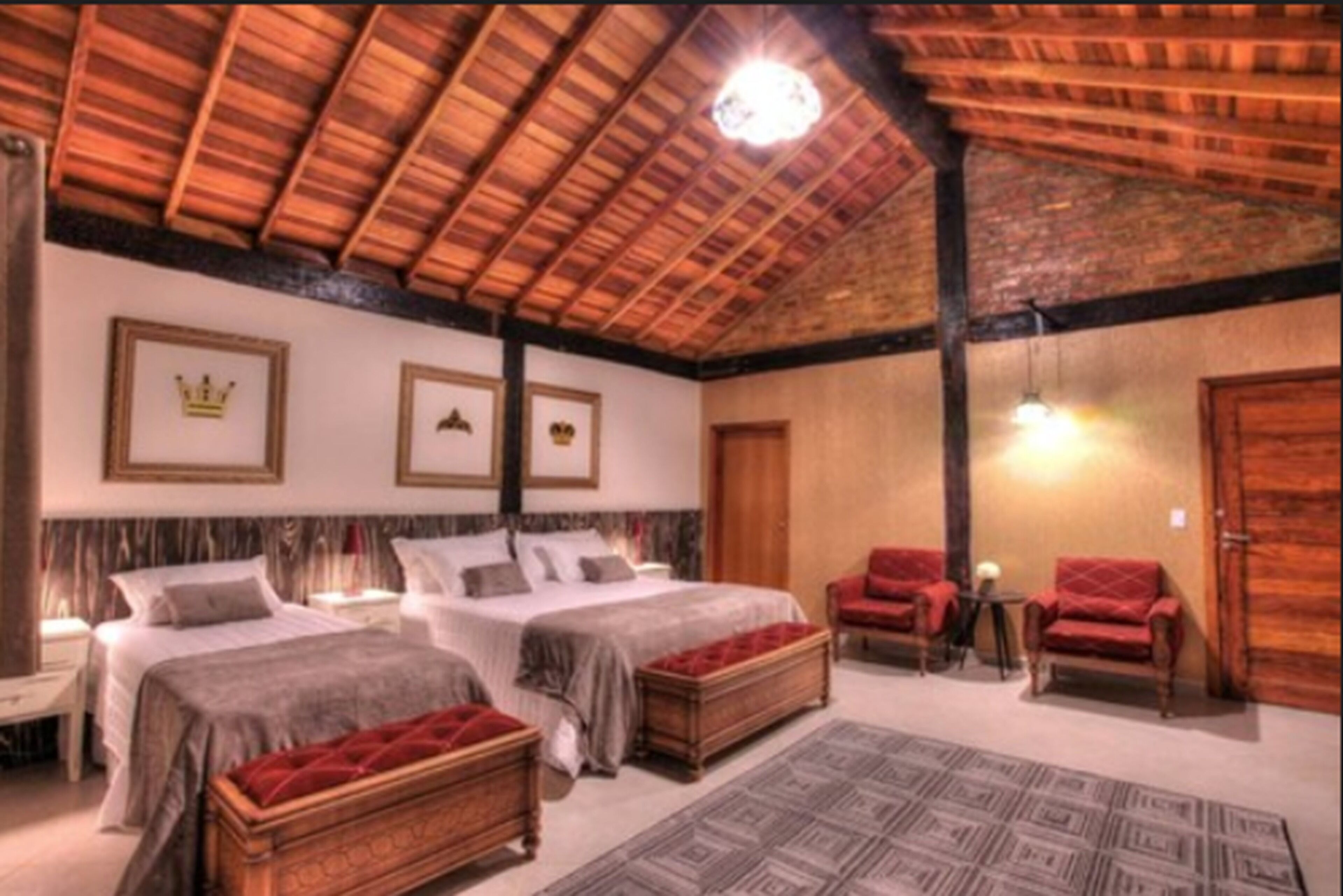 Quarto com duas camas, teto de madeira e tapete estampado.