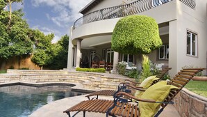 Uma área à beira da piscina com espreguiçadeiras e um jardim bem cuidado.