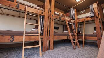 Quarto com beliches de madeira, camas numeradas e escadas.
