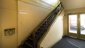 Uma escadaria com uma placa indicando 'Accommodation' e uma porta com vista para carros estacionados lá fora.