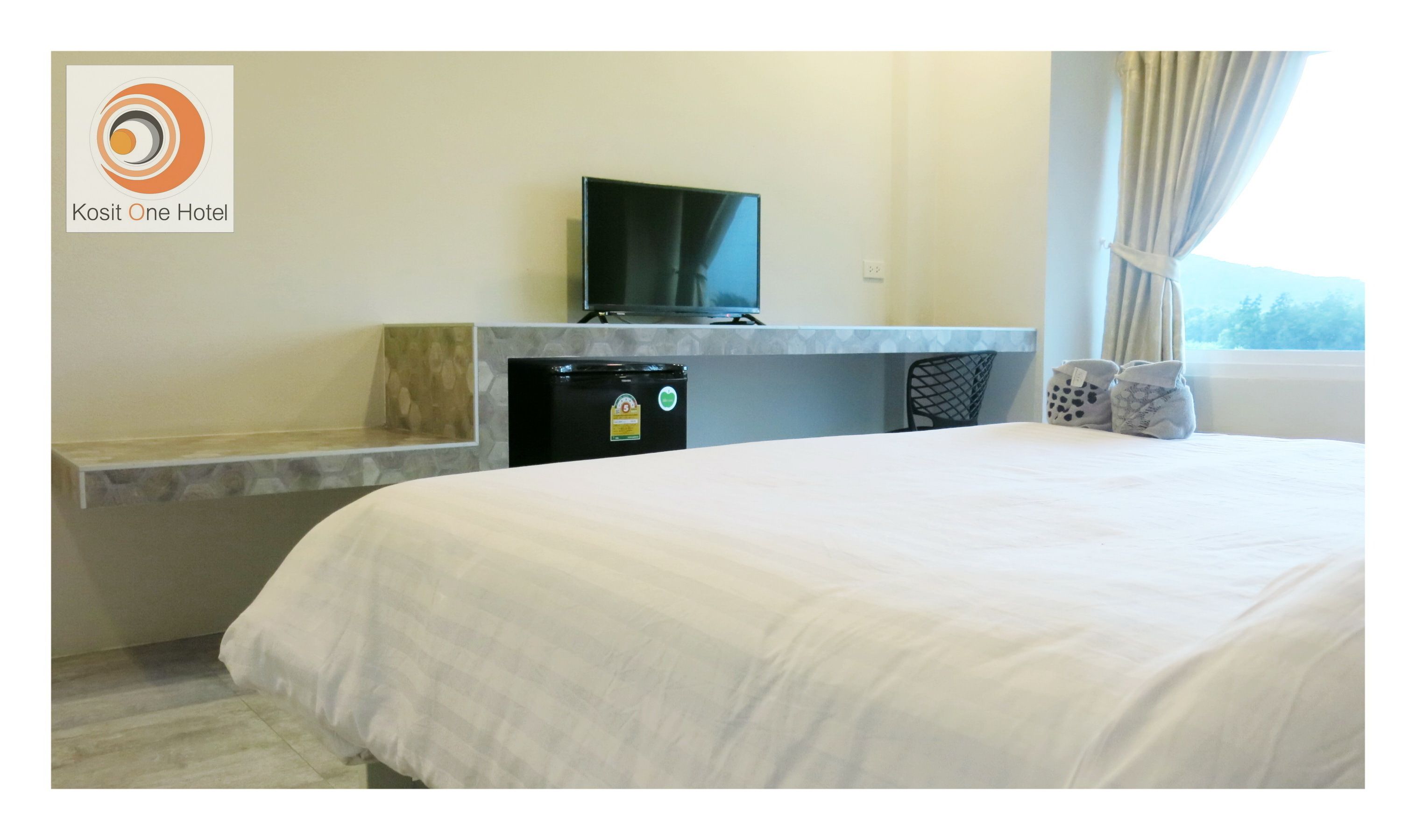 Quarto de hotel com cama, televisão, minibar e janela com cortinas.