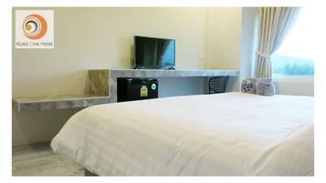 Quarto de hotel com cama, televisão, minibar e janela com cortinas.