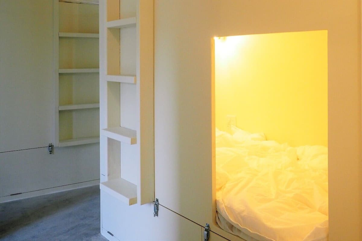 Quarto com uma cama, um guarda-roupa branco e uma estante.
