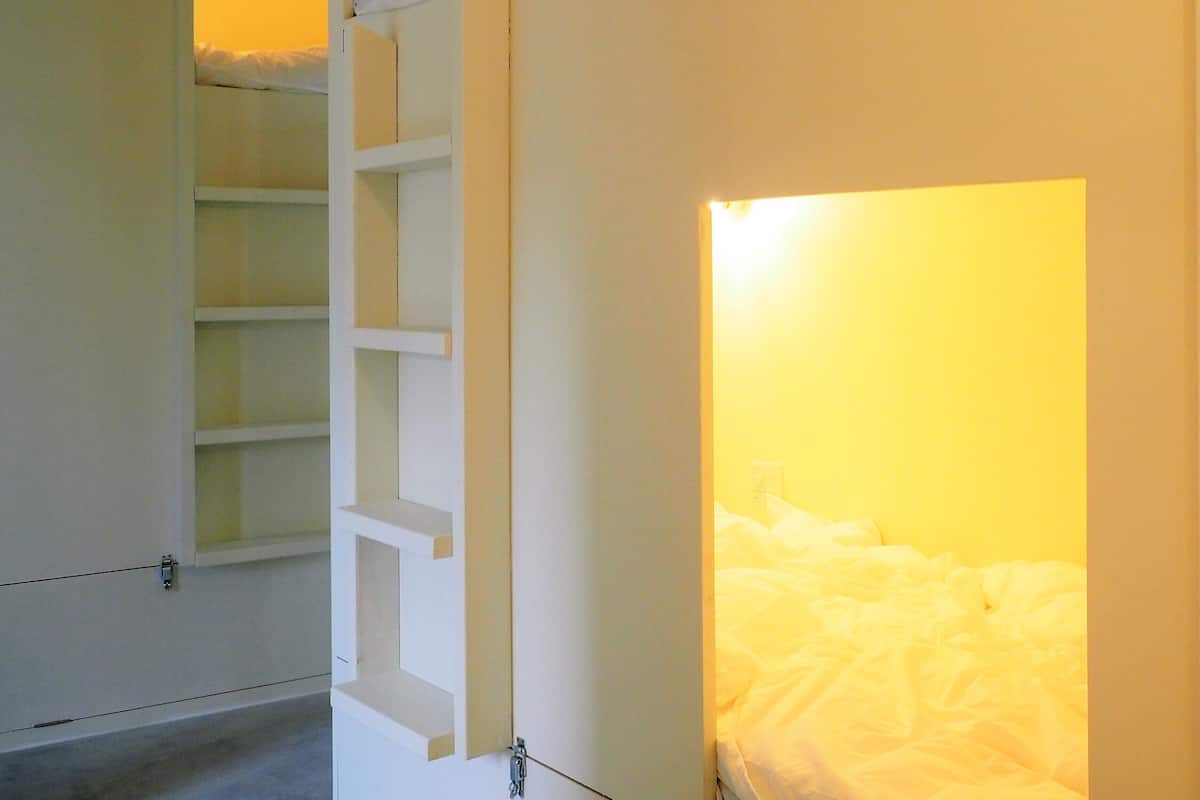 Quarto com cama, um guarda-roupa branco e uma estante.