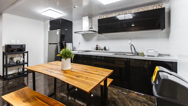 Cozinha moderna com armários pretos, mesa de madeira e um banco.