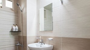 Casa de banho moderna com sanita, lavatório e chuveiro.