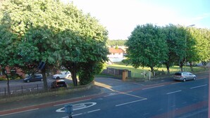 Uma estrada com sinal de velocidade, árvores e carros estacionados.