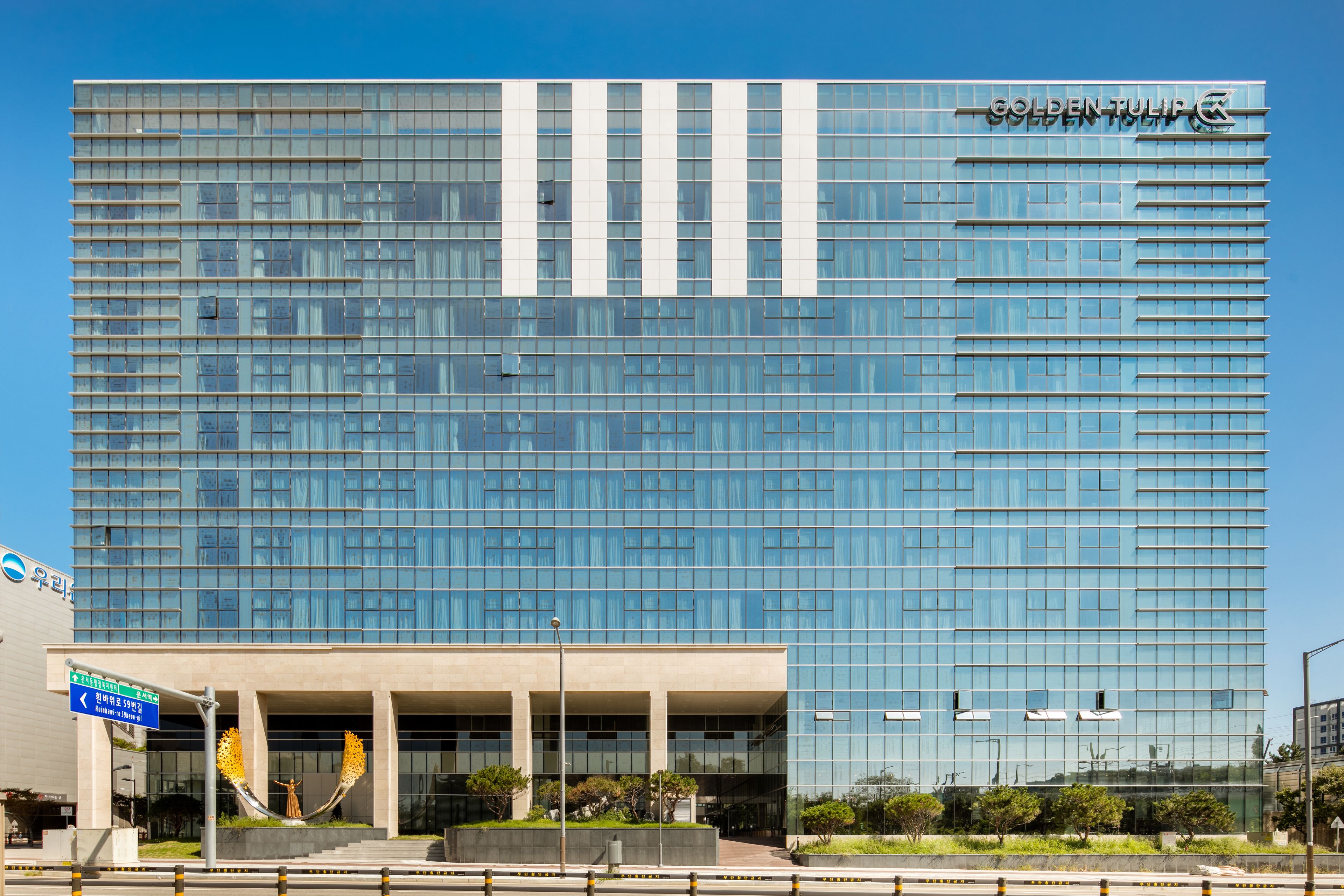 Um edifício moderno de vidro com uma placa que diz 'Golden Tulip'.