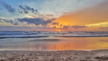 Uma praia com ondas e um pôr do sol.