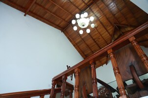 Uma escada de madeira com teto de madeira e um candelabro.