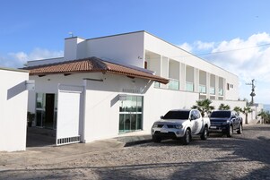 Um edifício moderno com fachada branca e telhado ladrilhado. Dois veículos estão estacionados na frente.