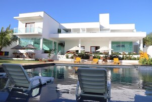 Um hotel moderno com área de piscina, incluindo cadeiras de descanso e guarda-sóis.
