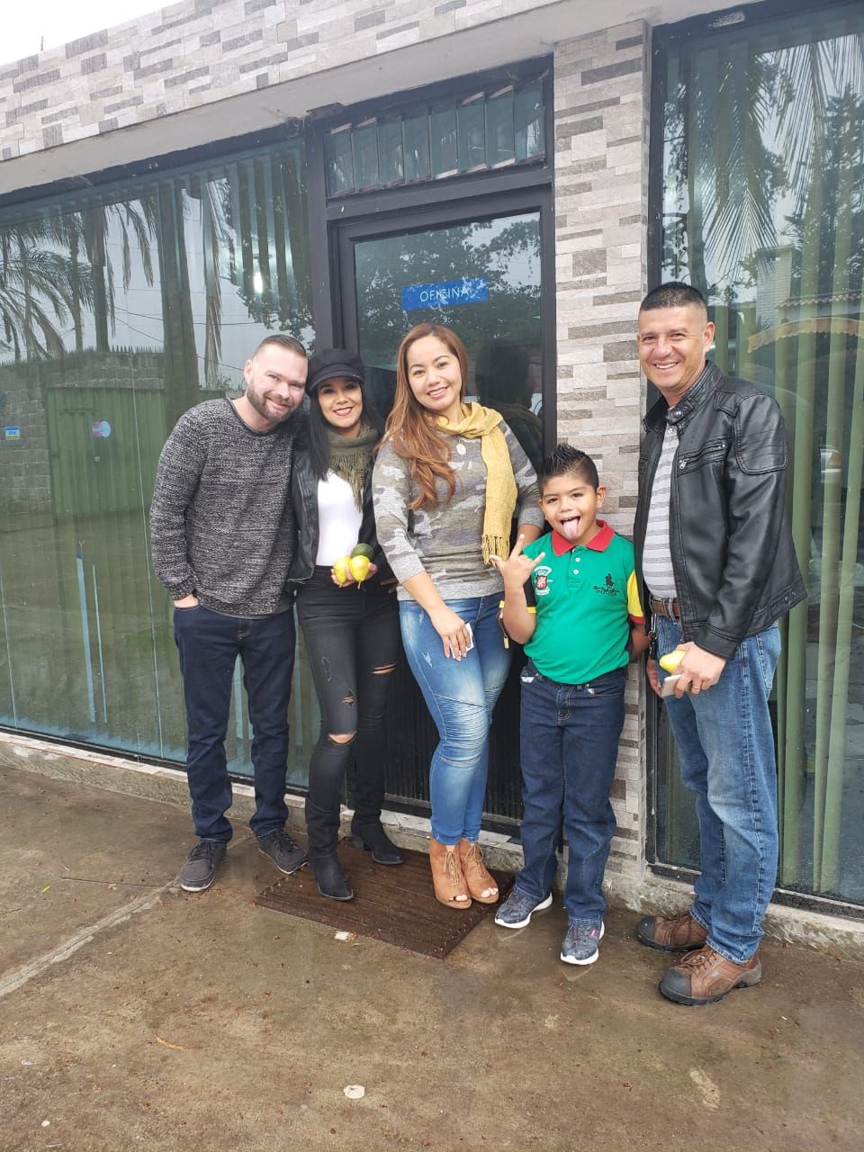 Uma família de quatro pessoas em frente a um edifício com porta e janelas de vidro.