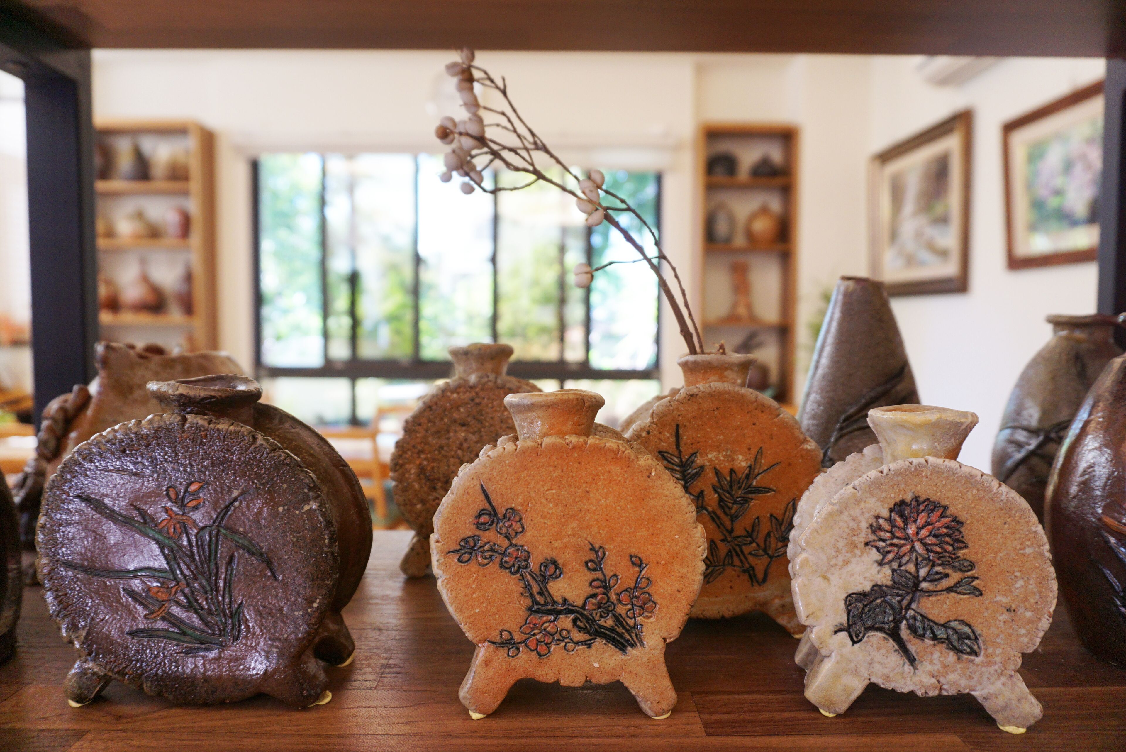 Conjunto de vasos de cerâmica com motivos florais sobre uma mesa de madeira.