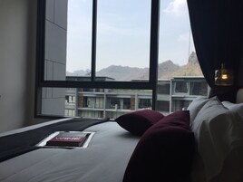 Quarto com uma janela grande, uma cama com almofadas e um livro na cama.