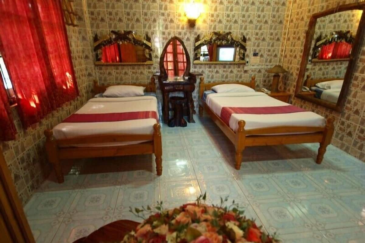 Quarto com duas camas de madeira, uma escrivaninha e um espelho.
