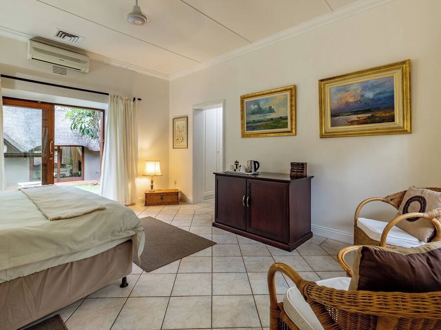 Quarto com cama, cômoda, cadeira e um quadro na parede.