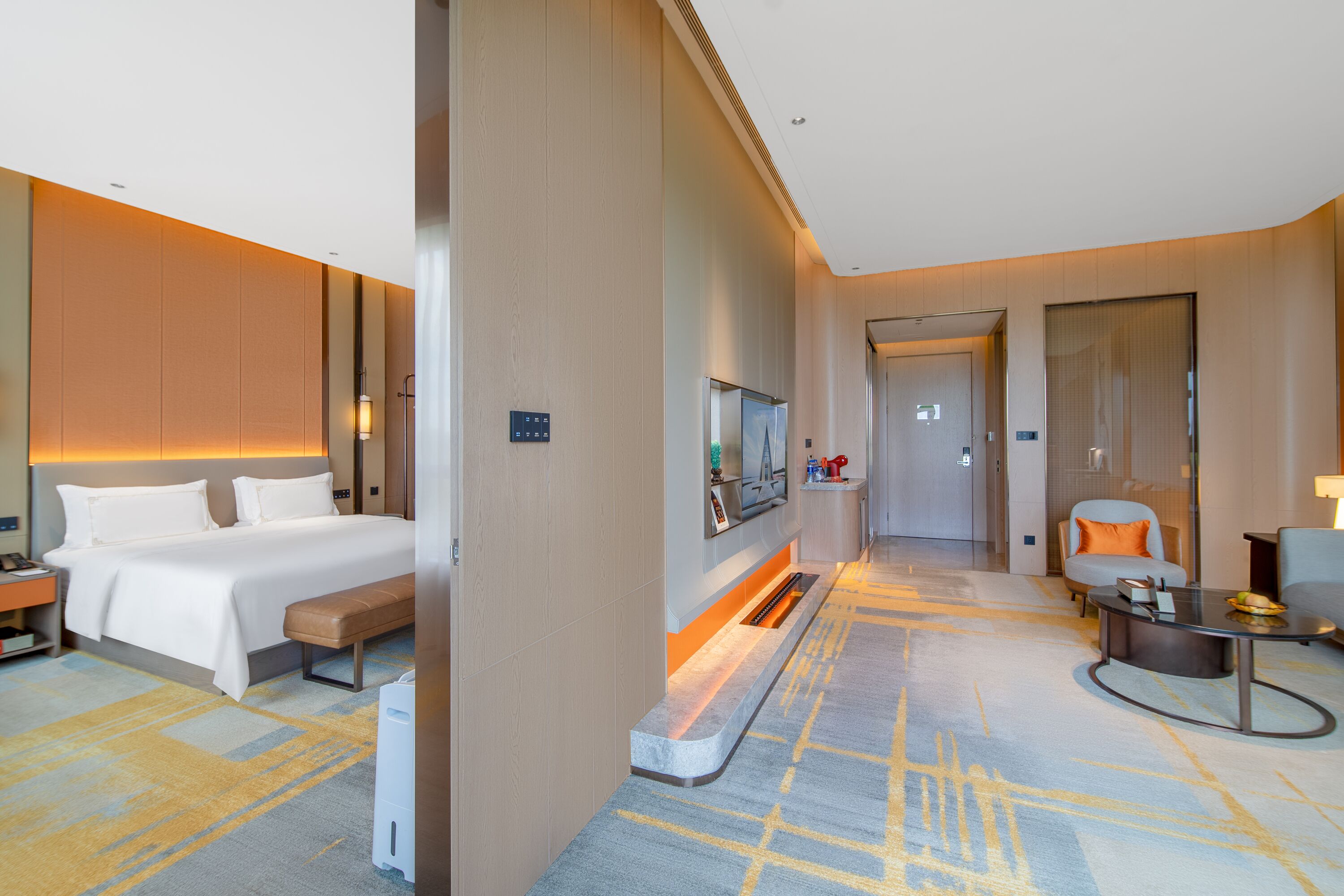 Quarto de hotel com cama grande, um banco, uma escrivaninha e televisão.