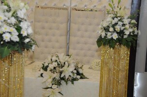 Um ambiente luxuoso com encosto estofado, arranjos florais e detalhes dourados decorativos.