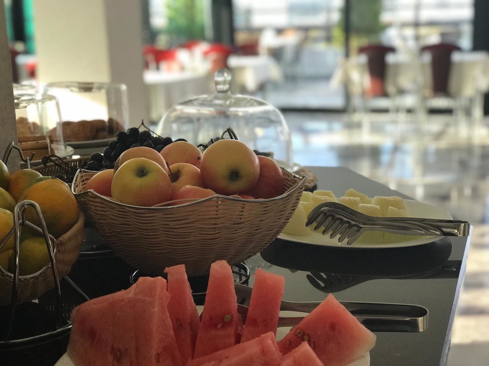 Buffet de café da manhã com diversas frutas e uma melancia.