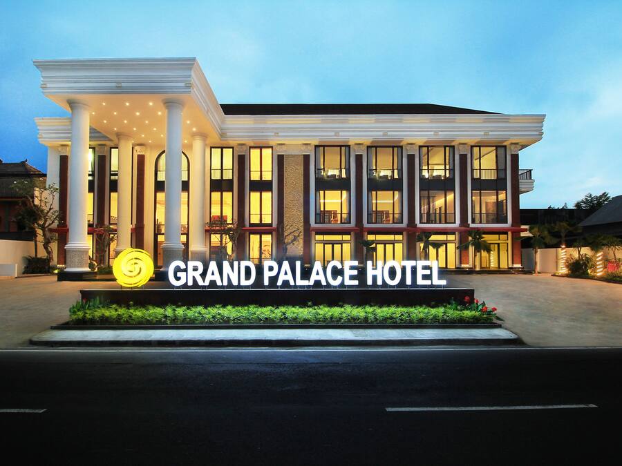 Exterior do Grand Palace Hotel, com uma entrada imponente, colunas grandes e fachada bem iluminada.
