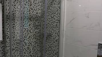 Um banheiro com chuveiro em box de vidro, um bidê e um vaso sanitário.