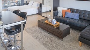 Uma sala de estar moderna com uma cama grande, um sofá, um espaço de refeições e uma varanda.