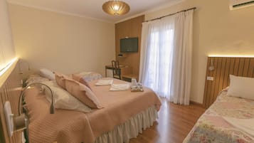 Quarto com cama, mesa de cabeceira, abajur e televisão na parede.