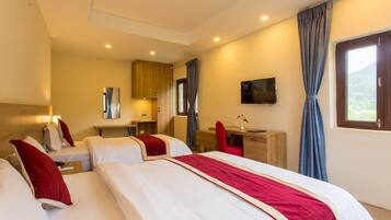 Quarto de hotel com duas camas, uma escrivaninha, uma cadeira, uma televisão e uma janela com cortinas.