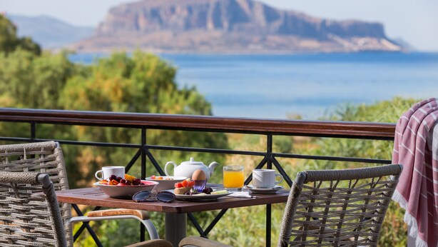 Mesa de jantar com itens de café da manhã e vista para uma paisagem montanhosa.