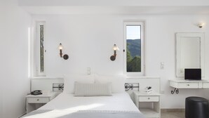 Quarto moderno com uma cama grande, mesas de cabeceira, escrivaninha, espelho e duas luminárias fixadas na parede.