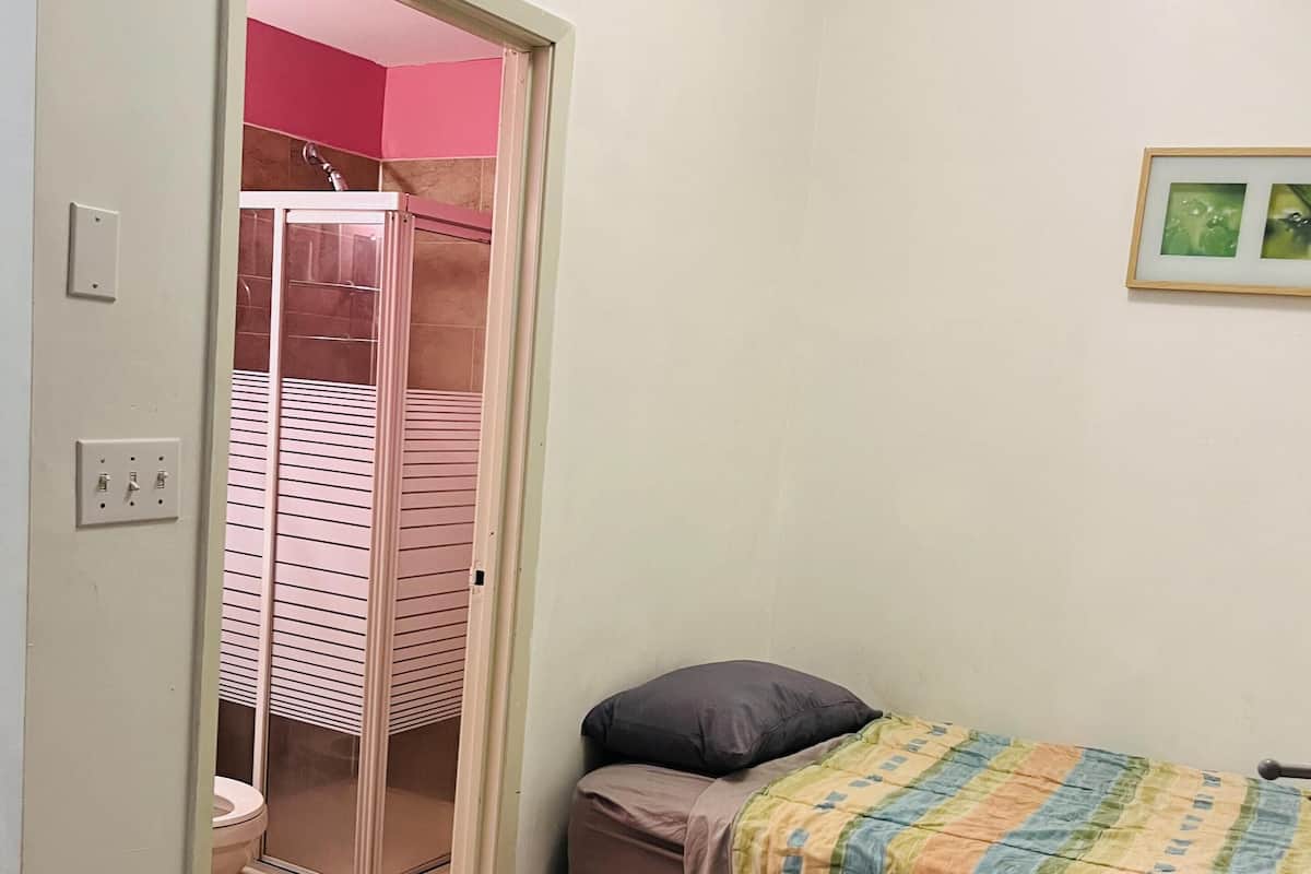 Quarto com cama, guarda-roupa e chuveiro.