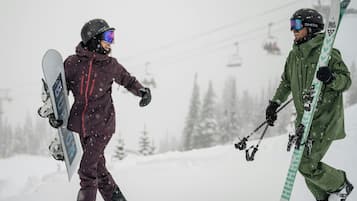 Dois esquiadores em um cenário nevado, um segurando uma prancha de snowboard e o outro esquis.